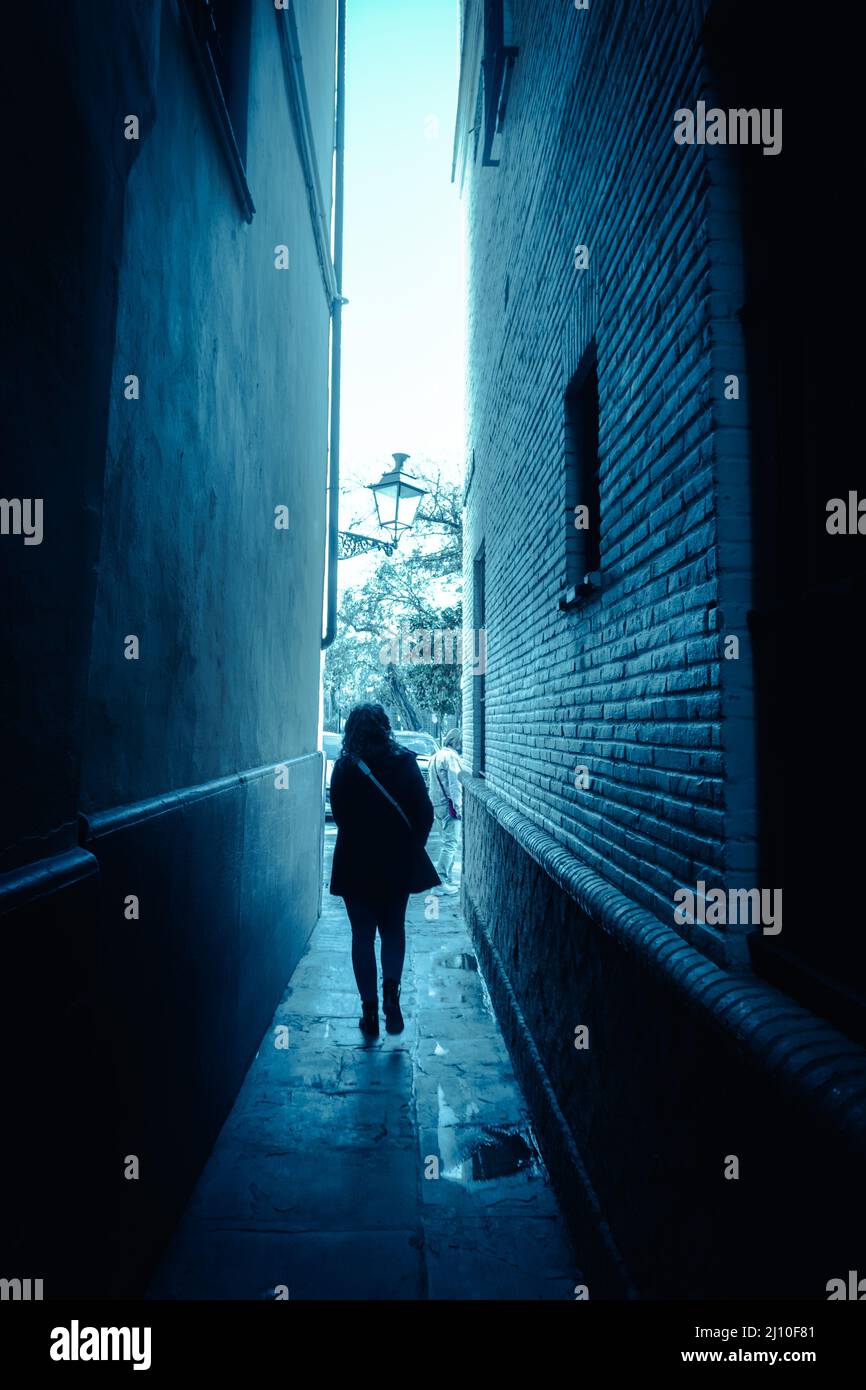Woman walking alone in a small pathway between old buildings Stock ...