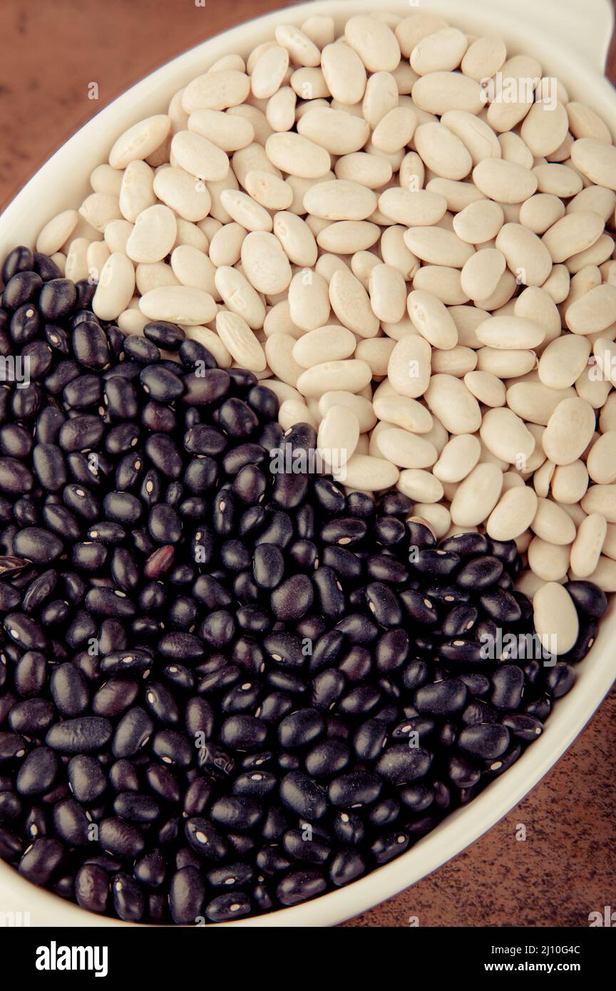 The photo shows black and white beans. The texture of the seeds is made ...