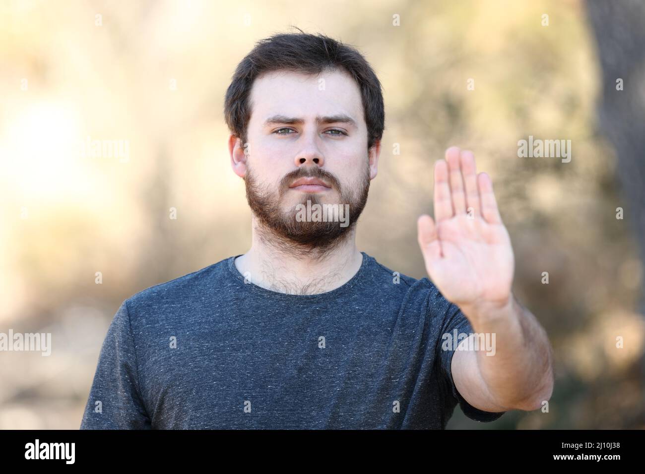 Front view portrait of an angry man gesturing stop with hand outdoors ...