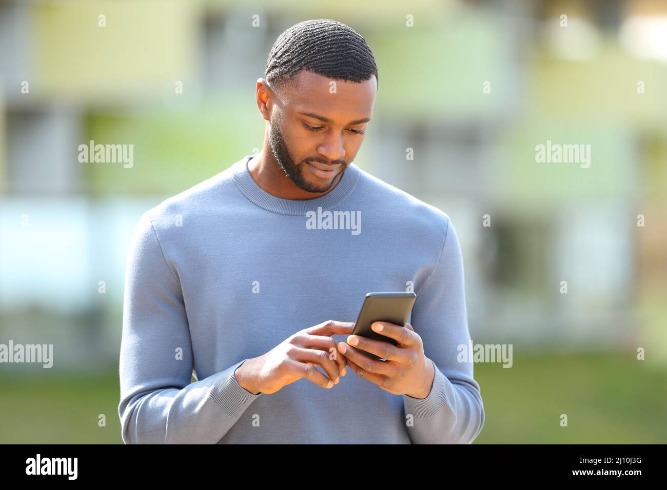 Front view portrait of a man with black skin checking cell phone in the ...