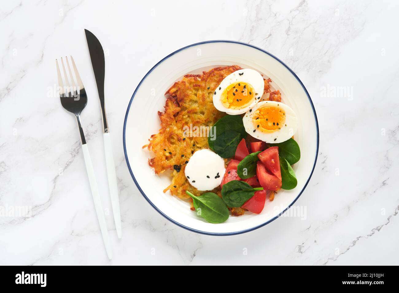 Breakfast. Potatoes latkes with sour cream, spinach salad, tomatoes and ...