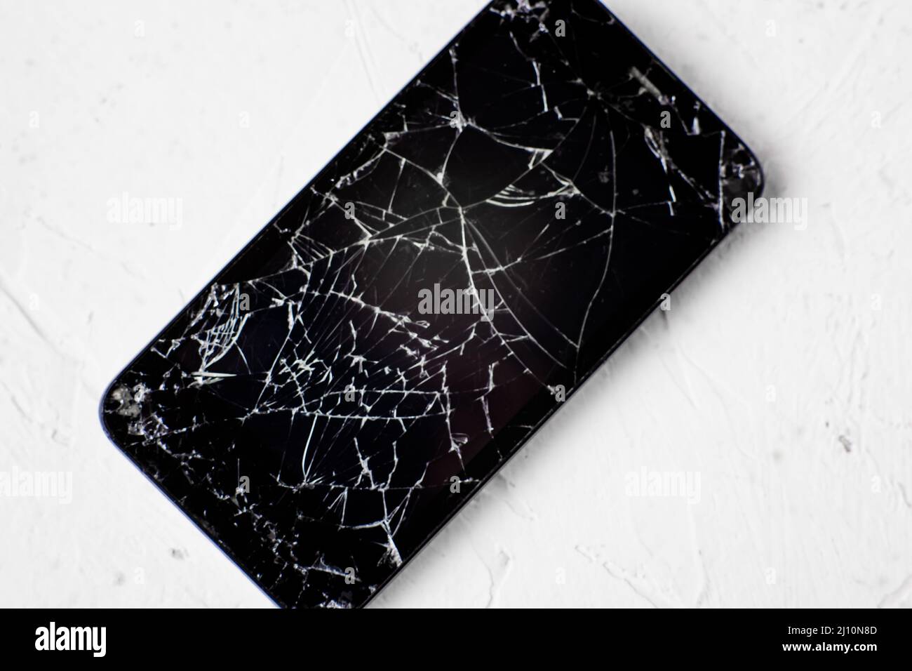 Broken phone screen on a white background. Many cracks on the black ...