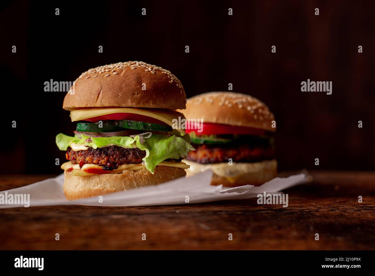 Two hamburgers on a wooden background. Big and small cheeseburger ...