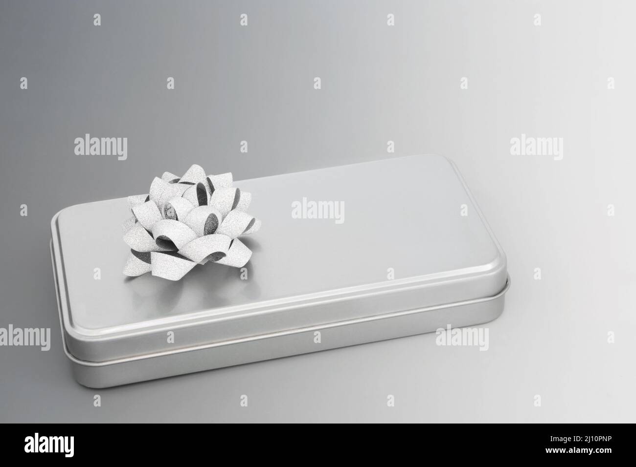 Brushed metal gift box with silver grey glitter bow on gradient grey ...
