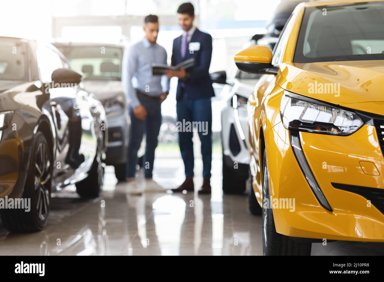Customer standing among cars, having conversation with sales assistant ...