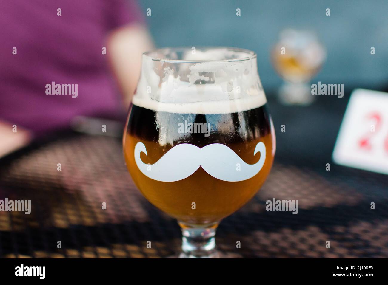 Beer pint with a mustache at an outdoor pub Stock Photo - Alamy