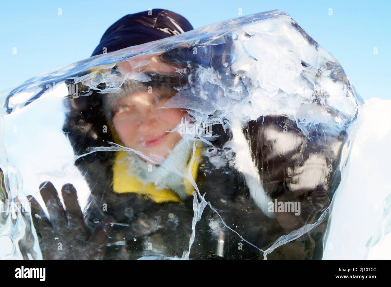 A woman looks through a transparent ice floe at Lake Baikal Stock Photo ...