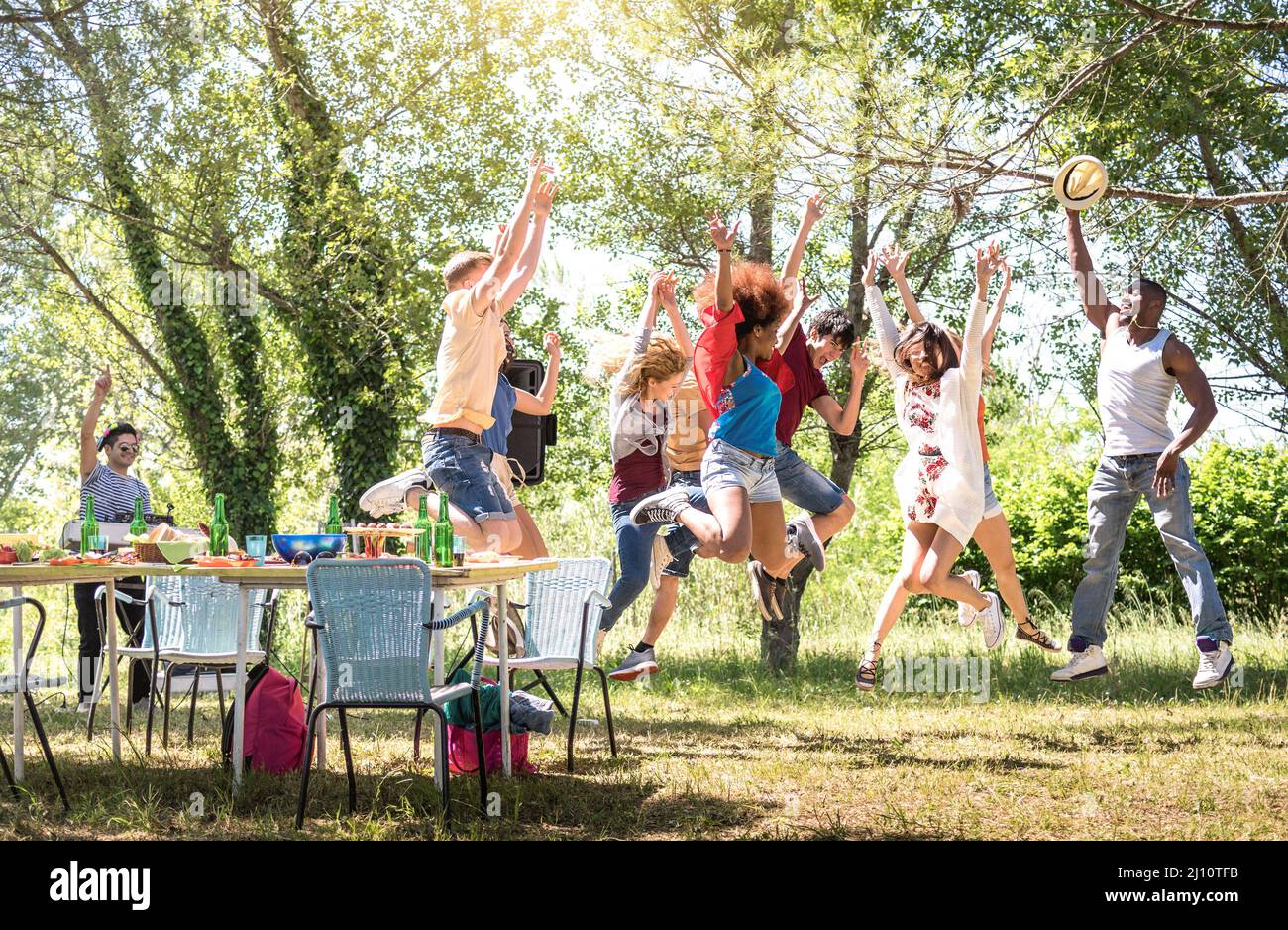 Multiracial friends jumping at barbecue pic nic garden party ...