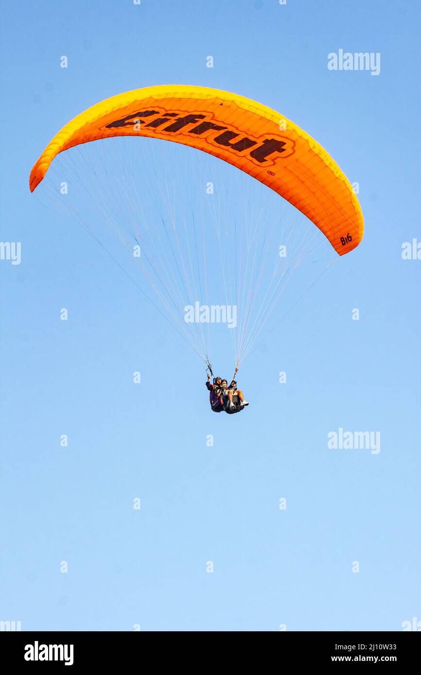 Vertical shot of an orange Paraglider with two people flying in Lima ...