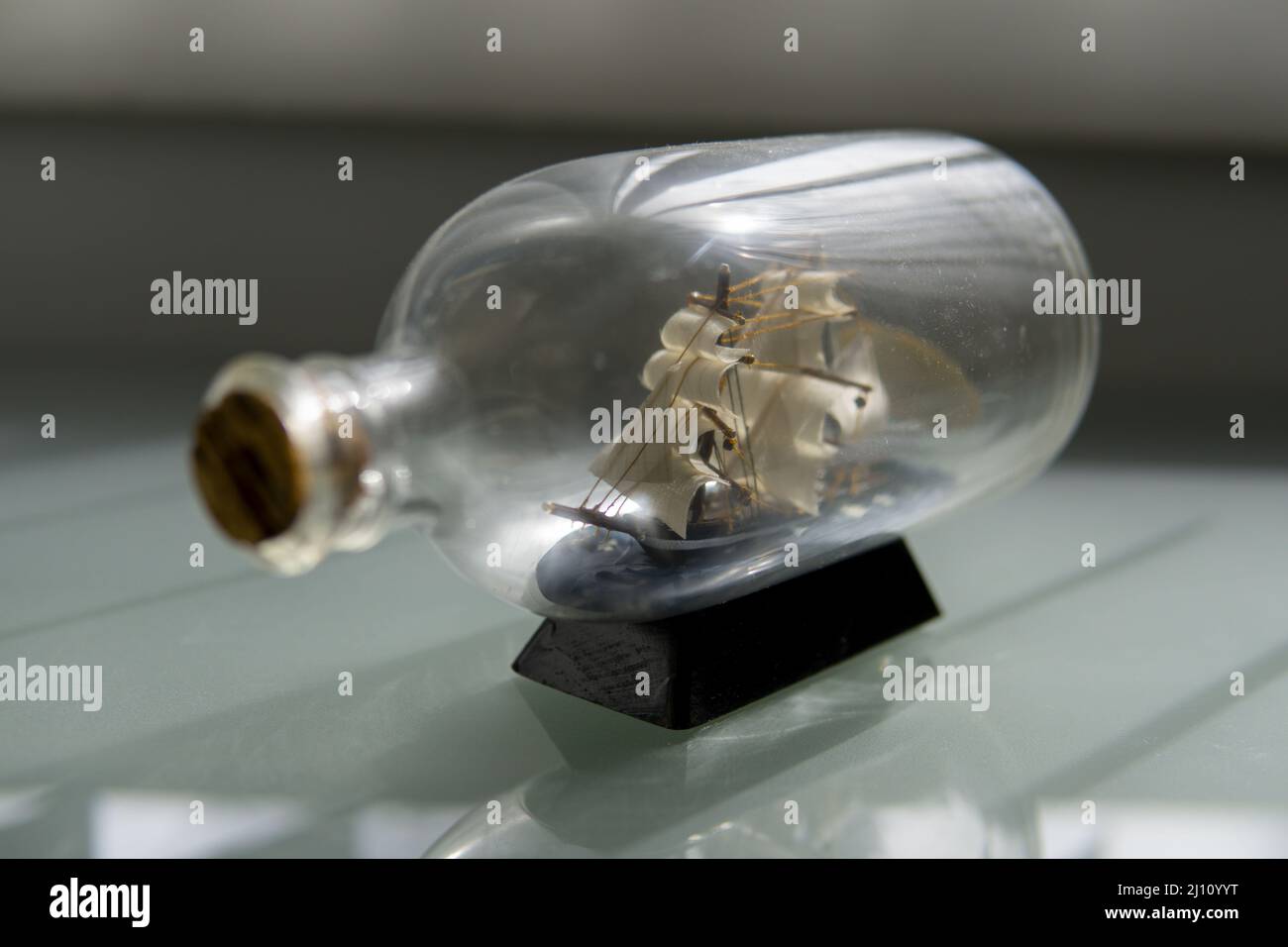 A closeup of an object ship inside a glass bottle on a glass surface ...