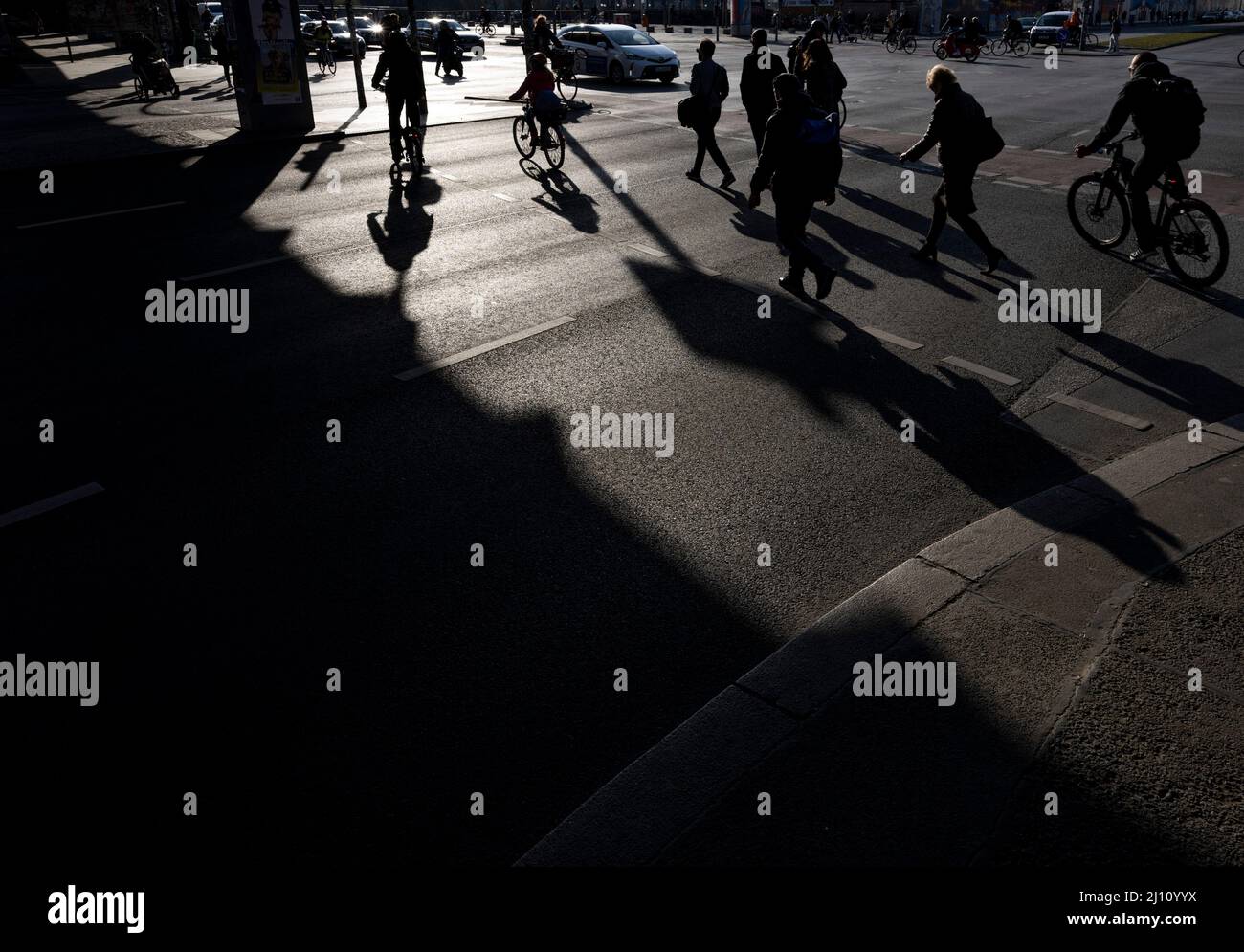 Berlin, Germany. 21st Mar, 2022. Passers-by walk across a street under ...