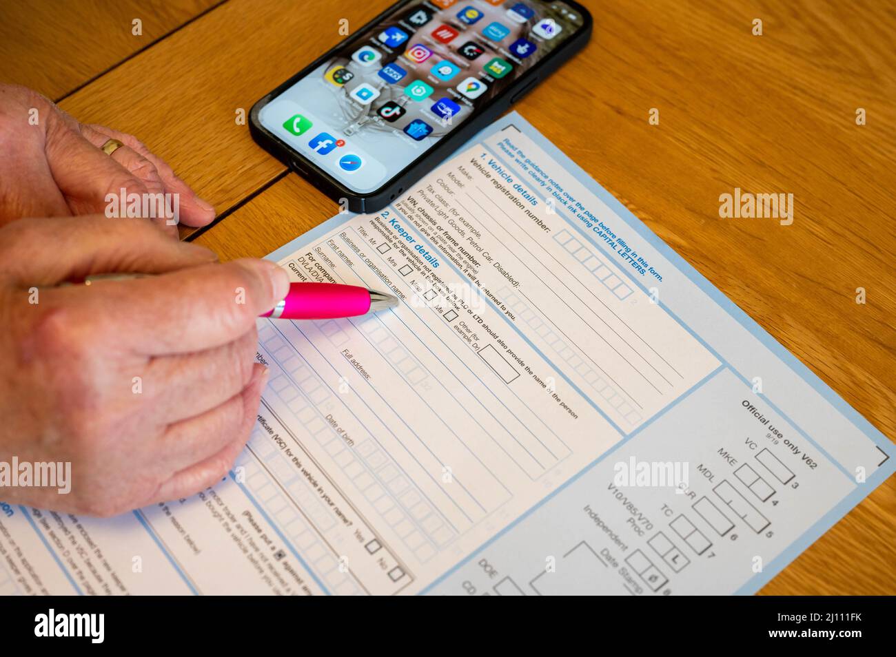 Lady with pen filling in DVLA form on desk in uk Stock Photo - Alamy