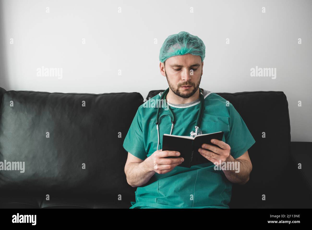 Doctor reading a book in the resting room ,wearing surgical gown Stock ...