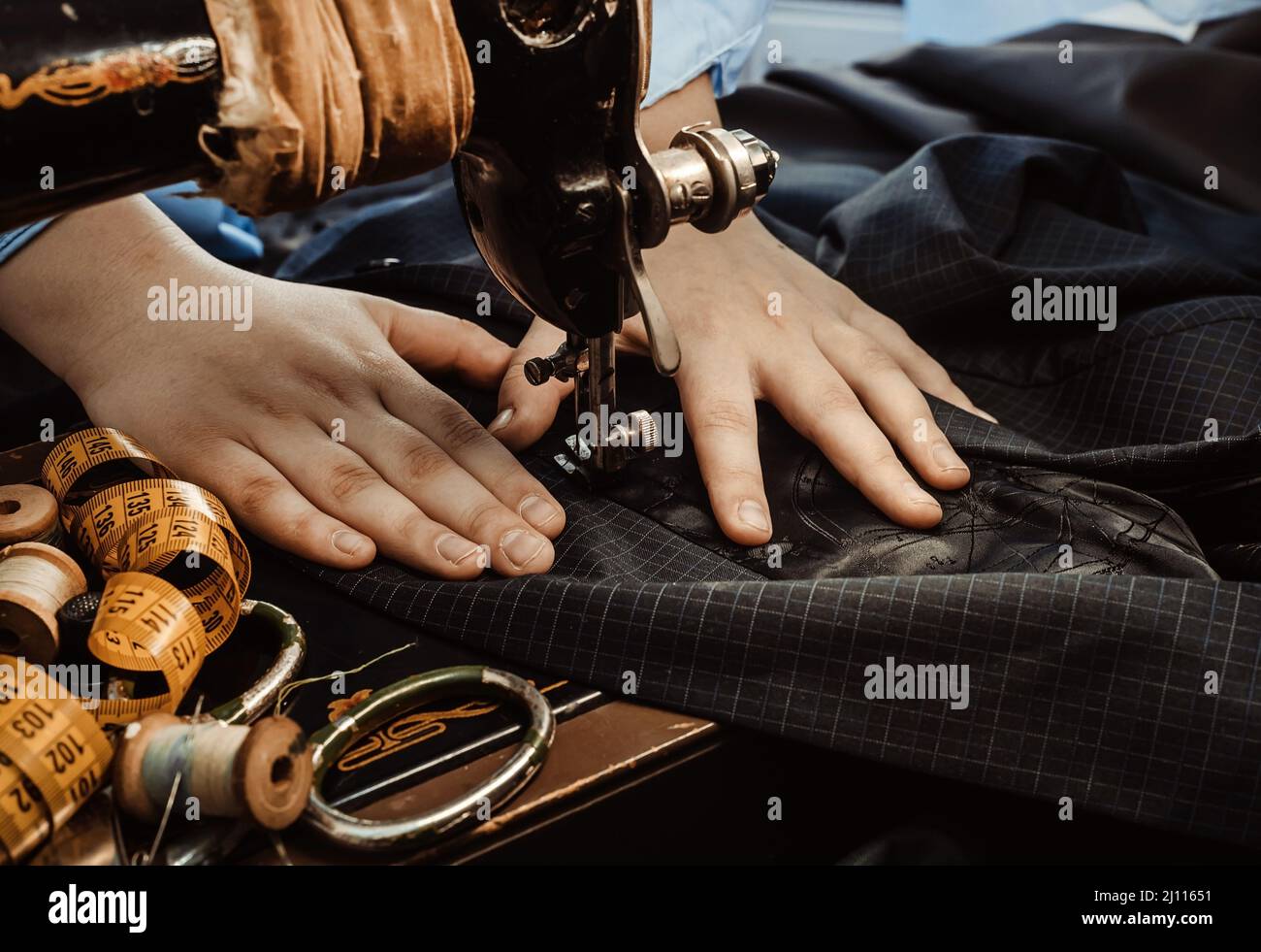 Tailor's hands close-up sew clothes on an old retro sewing machine ...