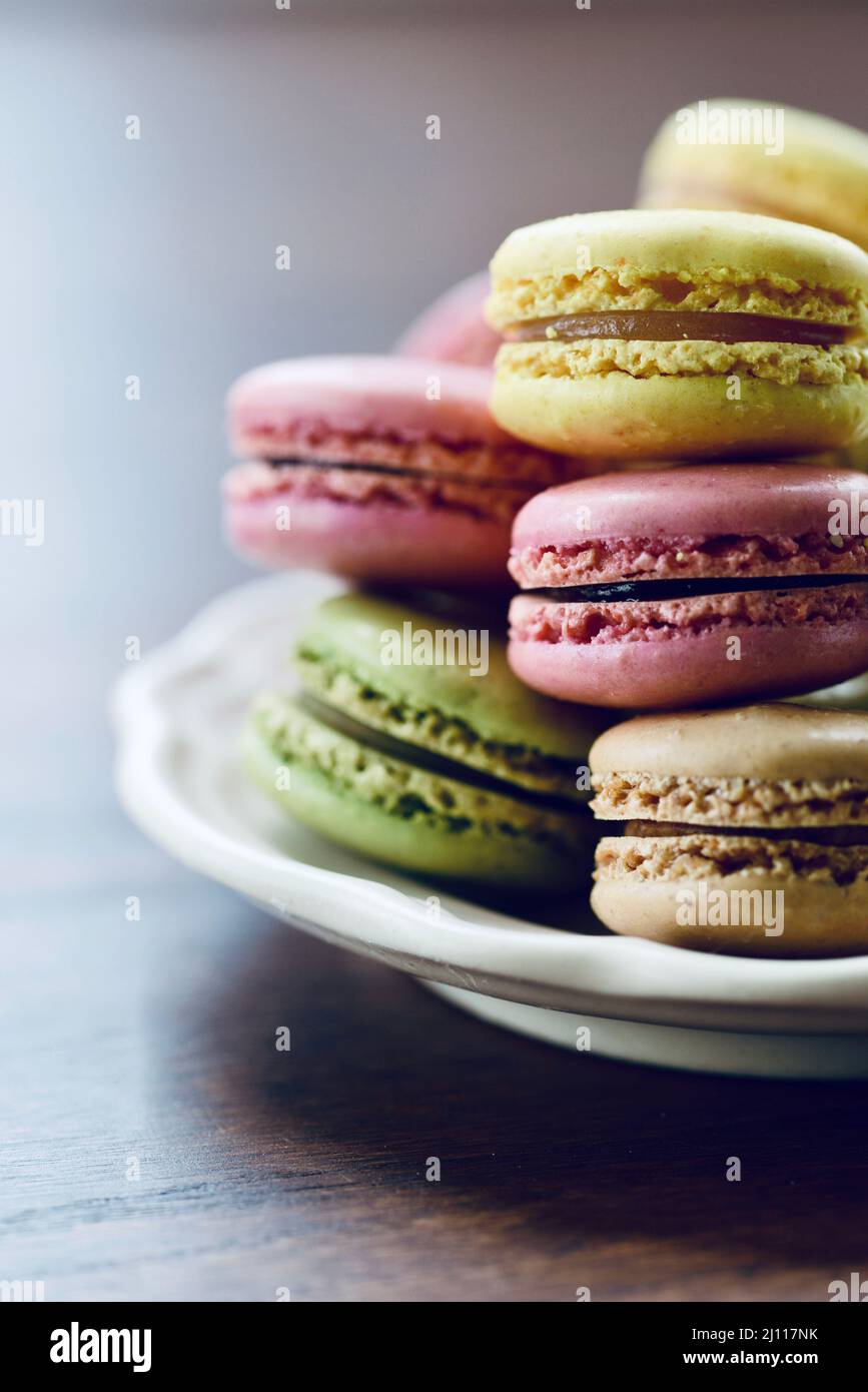 Raspberry, pistachio, lemon and caramel macarons piled high on a plate ...