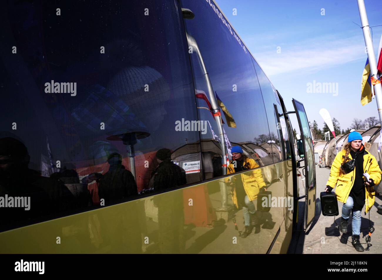 MEDYKA, POLAND - MARCH 20, 2022 - A woman in a blue hat and yellow coat ...