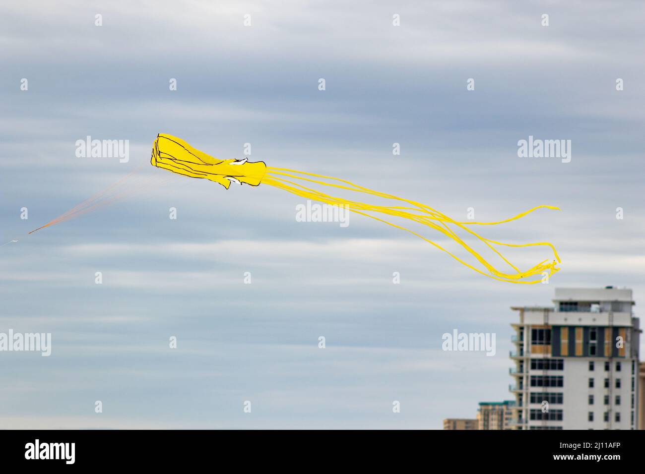 Closeup of a yellow kite flying high up in the blue sky Stock Photo - Alamy