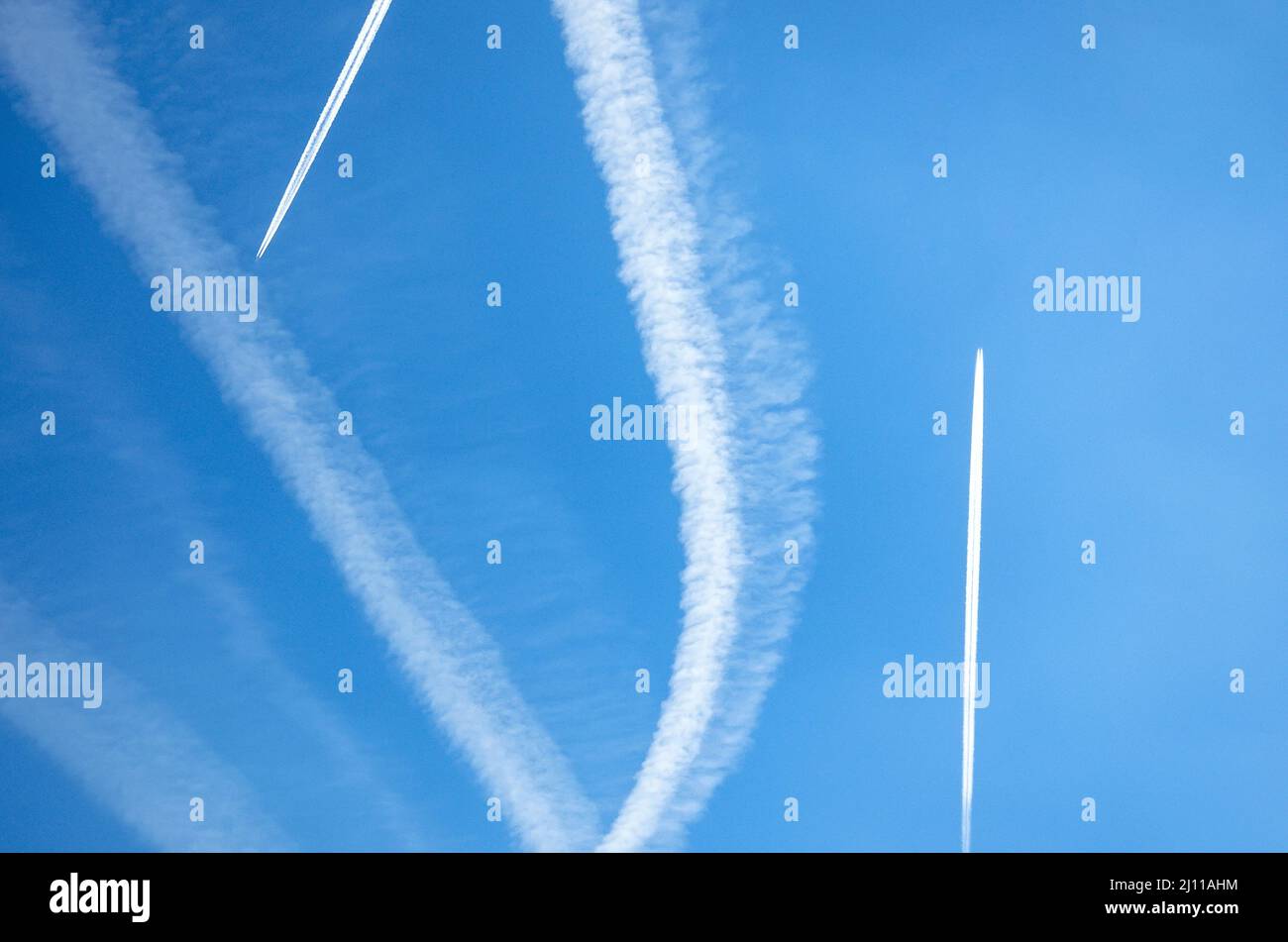 Contrails from airplanes high in the blue sky Stock Photo - Alamy