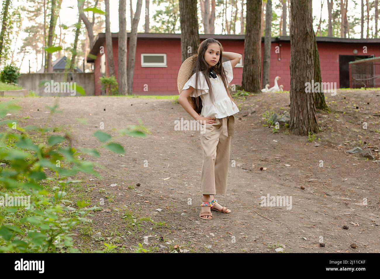 Preteen girl posing confidently on country estate in pine forest in ...