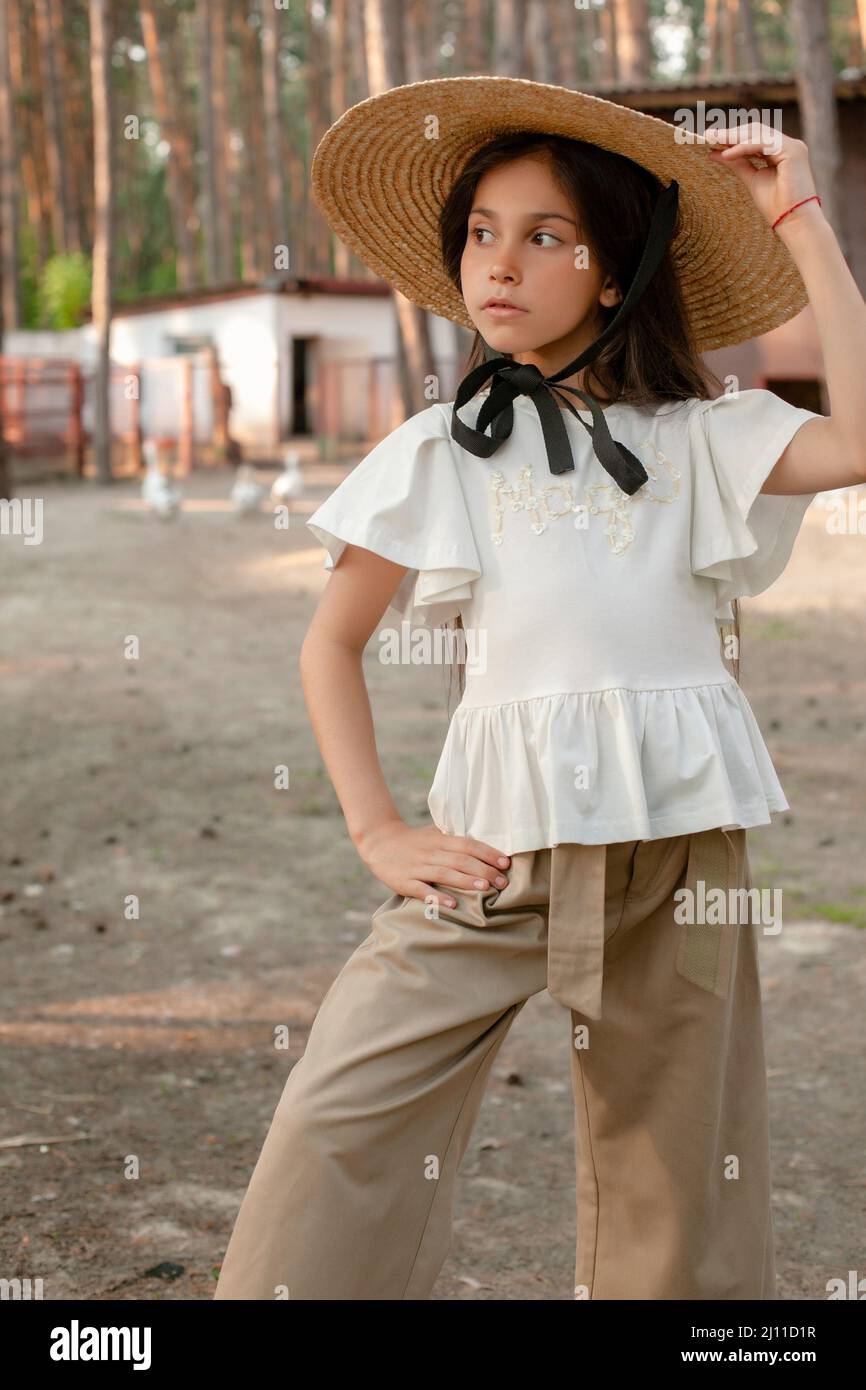 Stylish dark haired tween girl posing in backyard of country house in ...