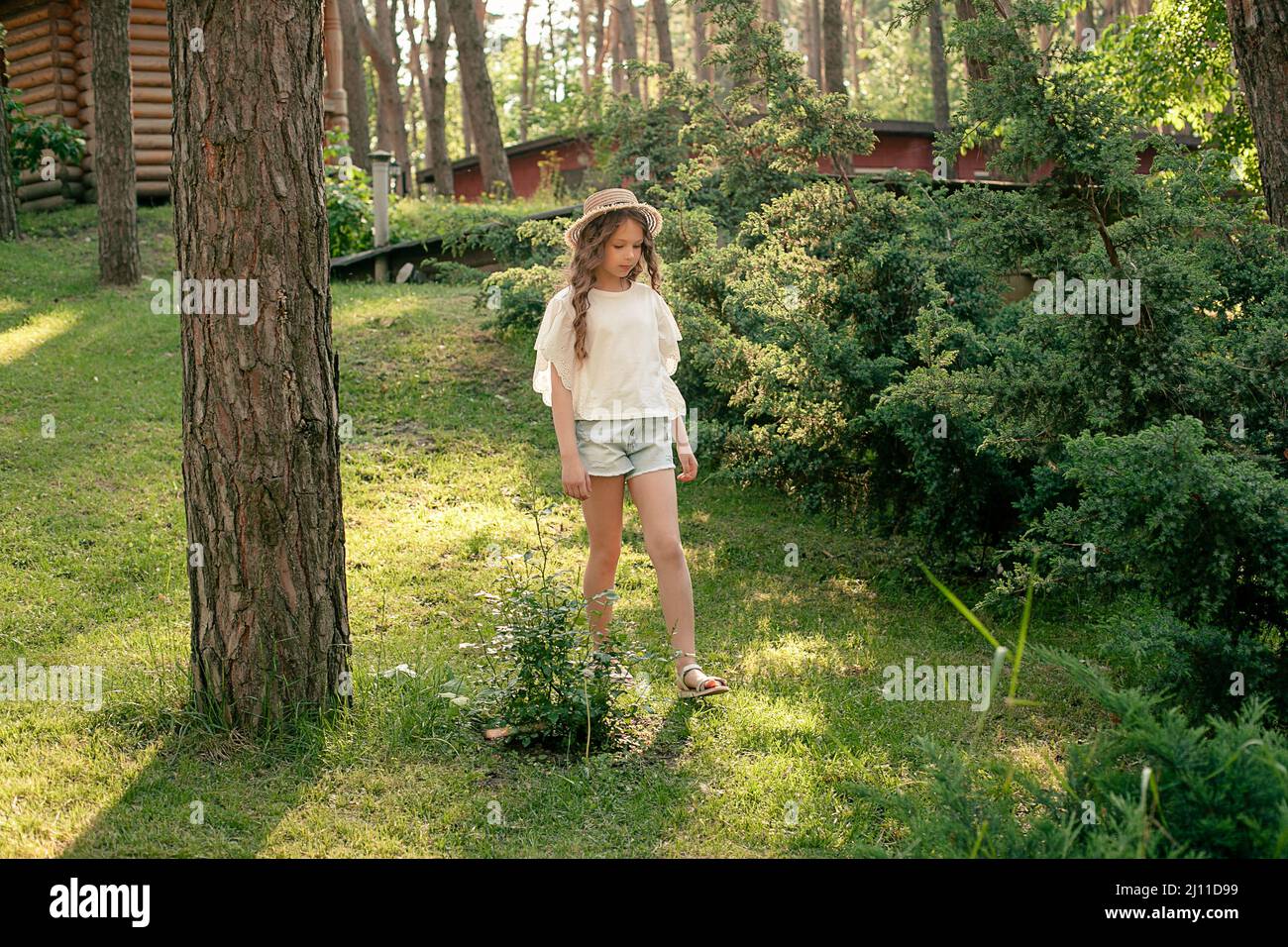 Relaxed tween girl walking in green park of country house on summer day ...