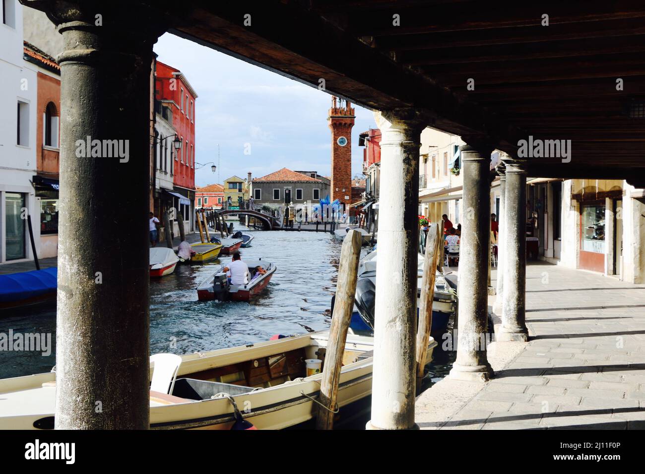 Shot of the colorful buildings with boats in river in Venice from under ...