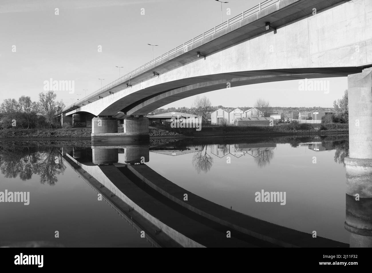 Grayscale shot of a white modern bridge with a bridge reflection on a ...