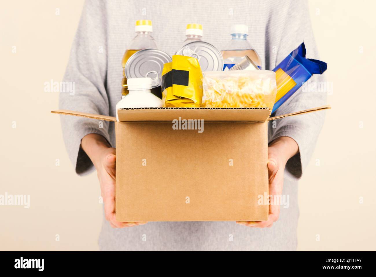 Woman hands holding cardbox with grocery products. Volunteer collecting ...