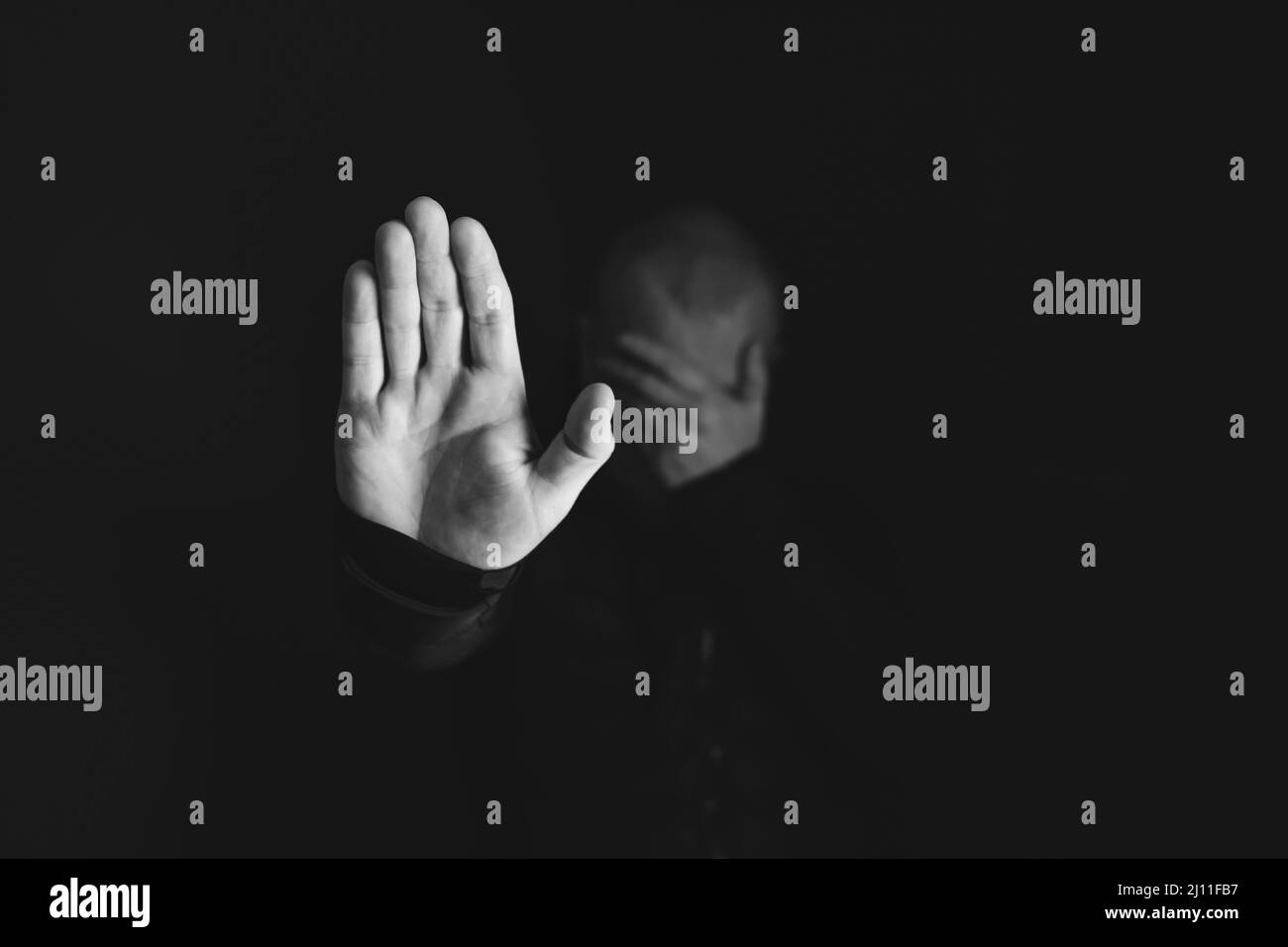Sad, angry man showing stop sign on dark background. Low key photo ...