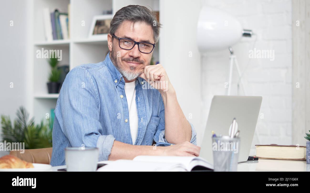 Happy older man working online with laptop computer at home sitting at ...