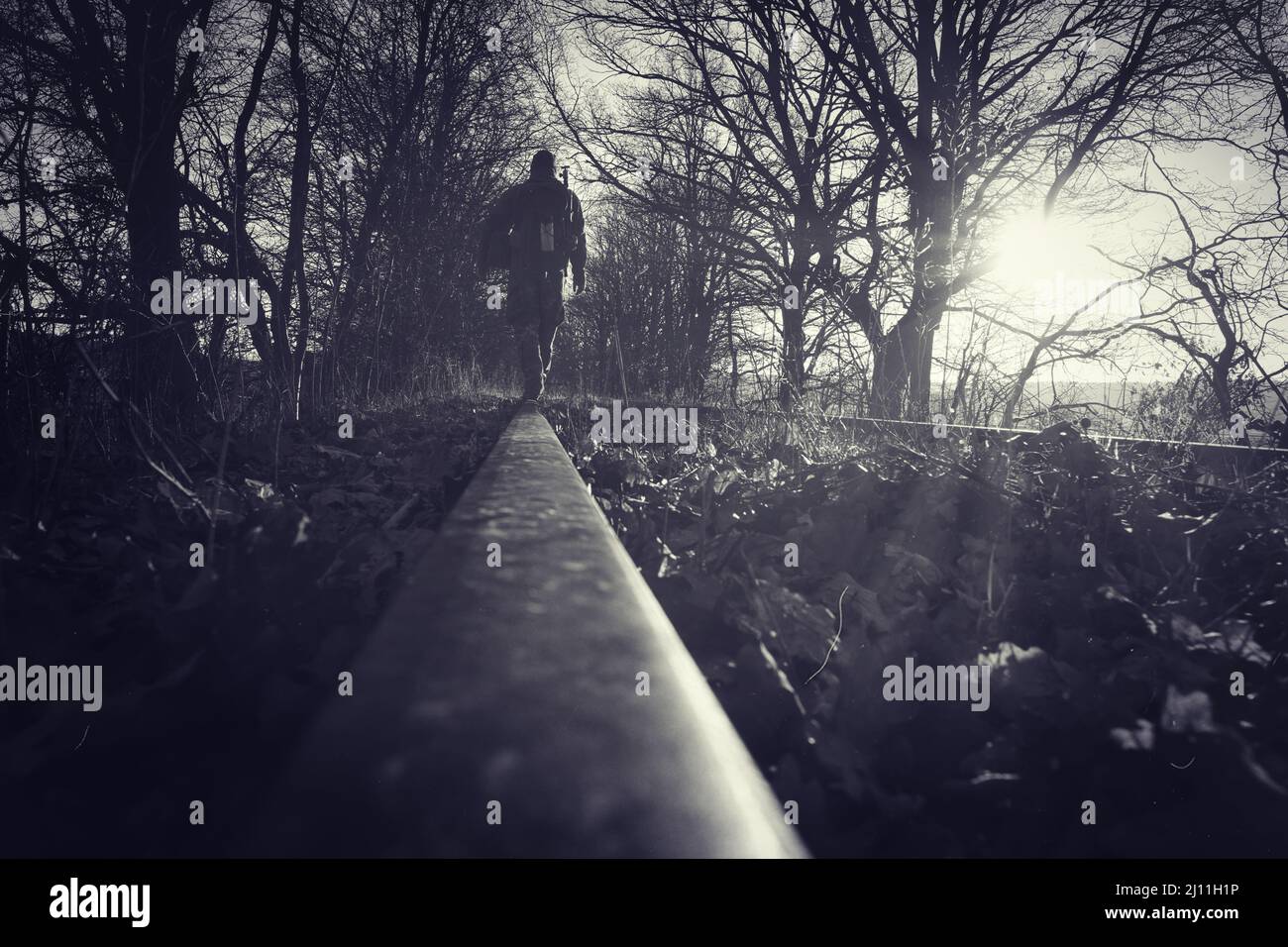Hiker walking across old abandoned and disused railroad tracks B&W ...