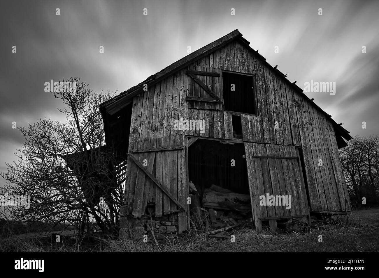 front view of an old spooky abandoned wooden barn with open door an ...