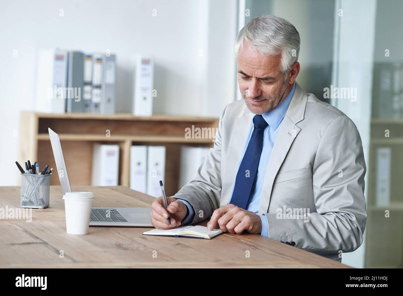 Getting down to business. Shot of a mature businessman working on a ...