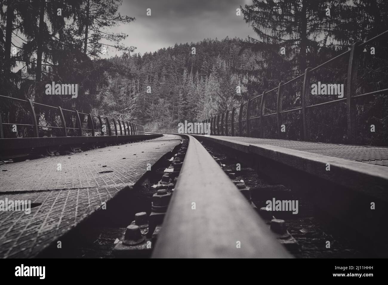 closeup shot of railroad tracks in front of an old iron railroad bridge ...