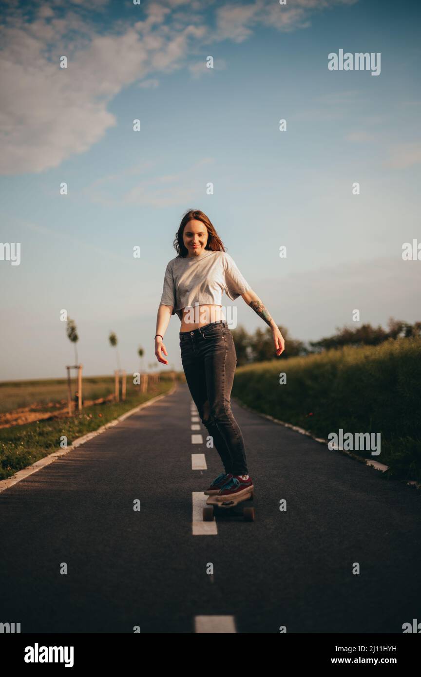 woman rides a longboard and enjoys free riding . poster, vertical ...