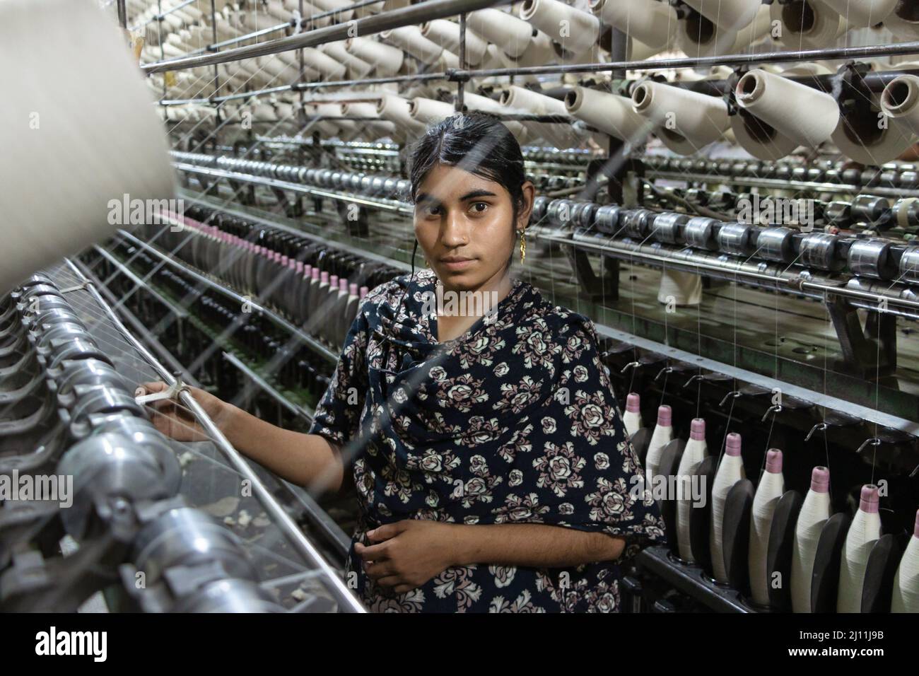 A worker is fixing threads at a textile factory in Narayanganj ...