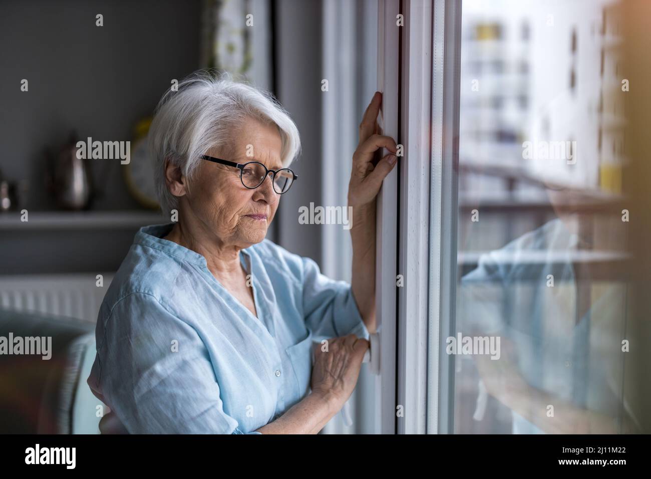 Senior woman looking out of window at home Stock Photo - Alamy