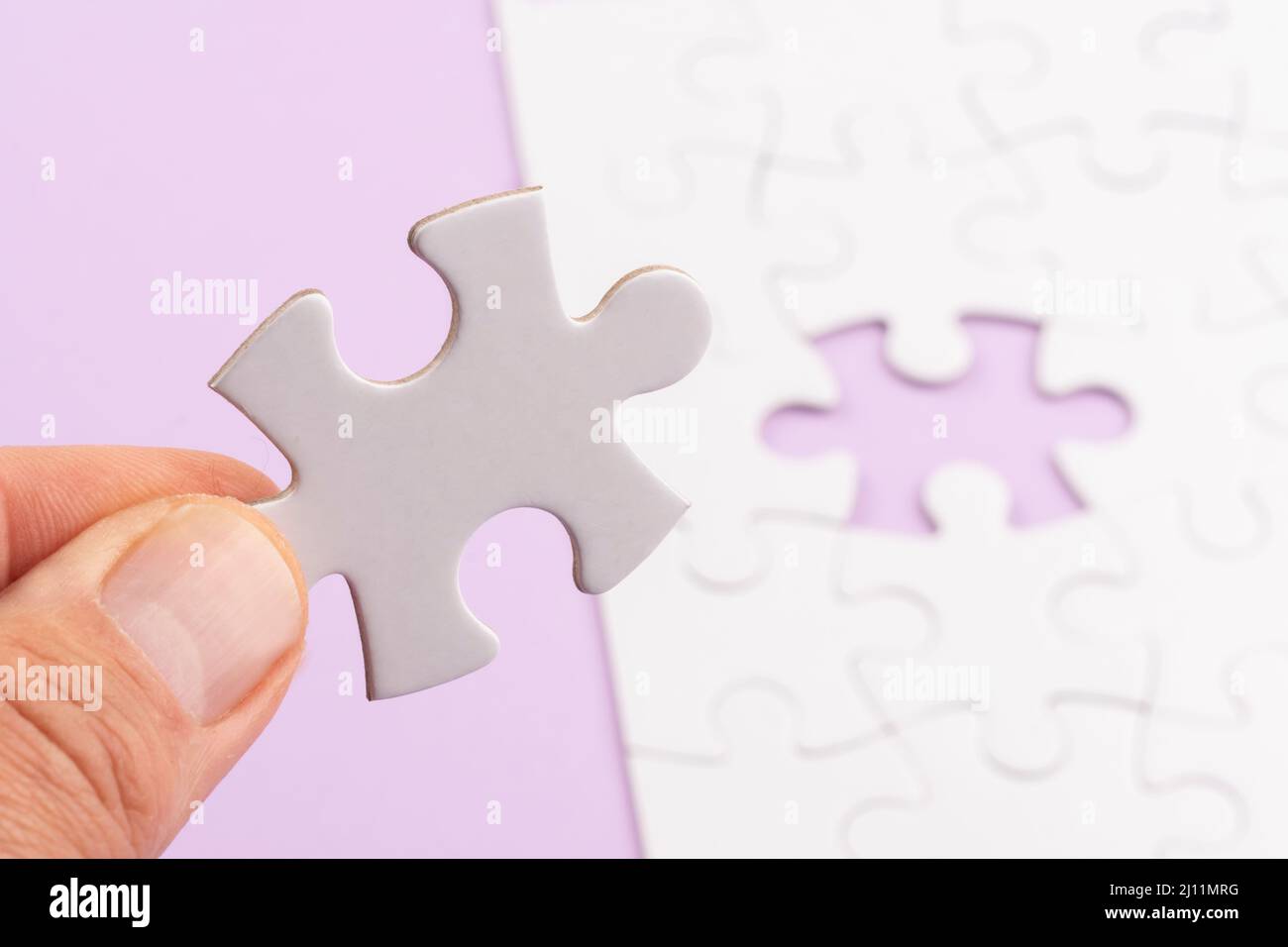 Hand holding Puzzle pieces on pink surface. White jigsaw game texture ...