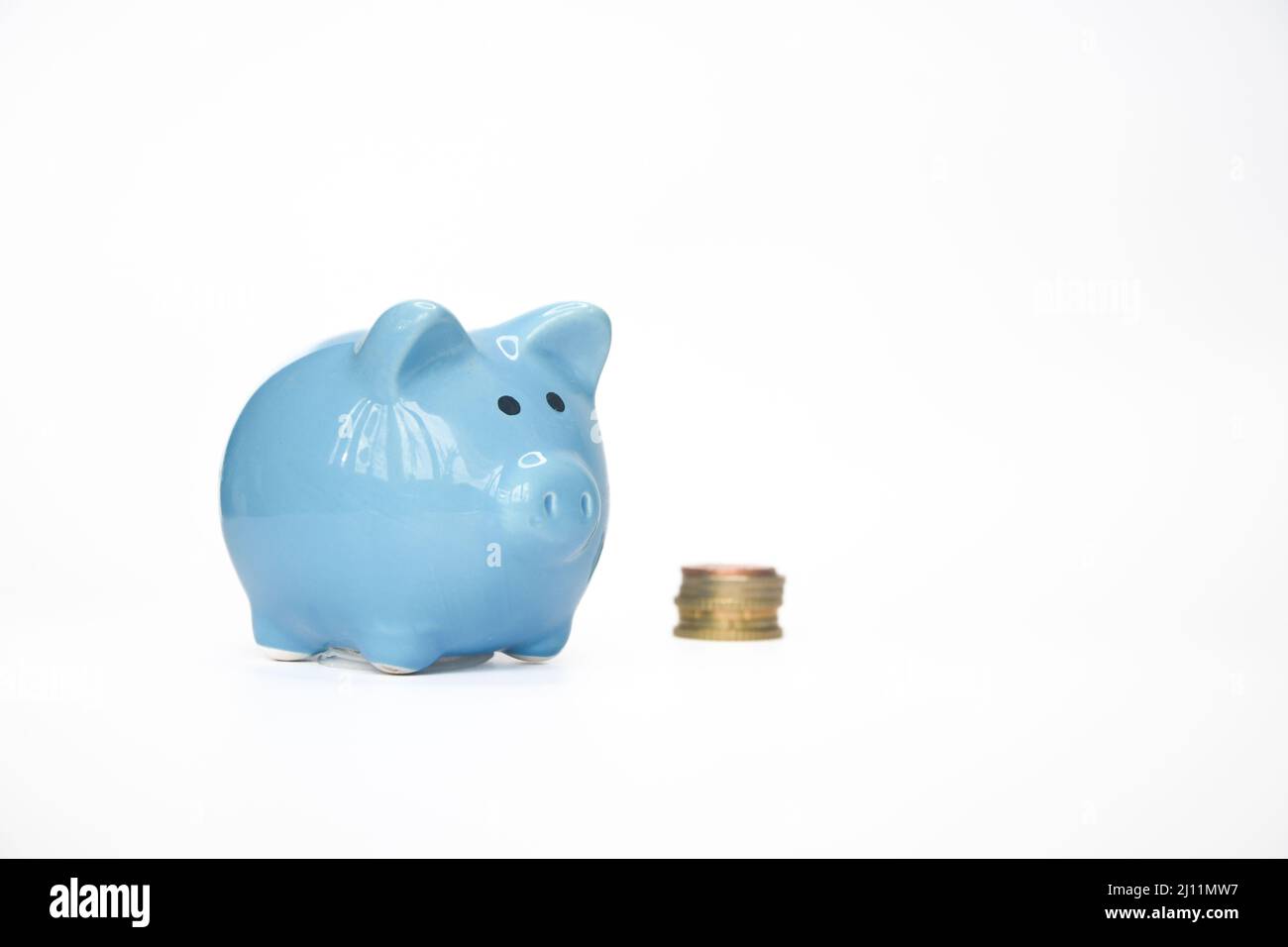 Photo of a blue piggy bank and coins, cash or money on white background ...