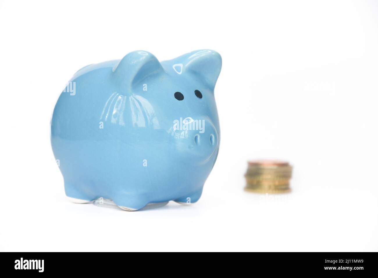 Photo of a blue piggy bank and coins, cash or money on white background ...