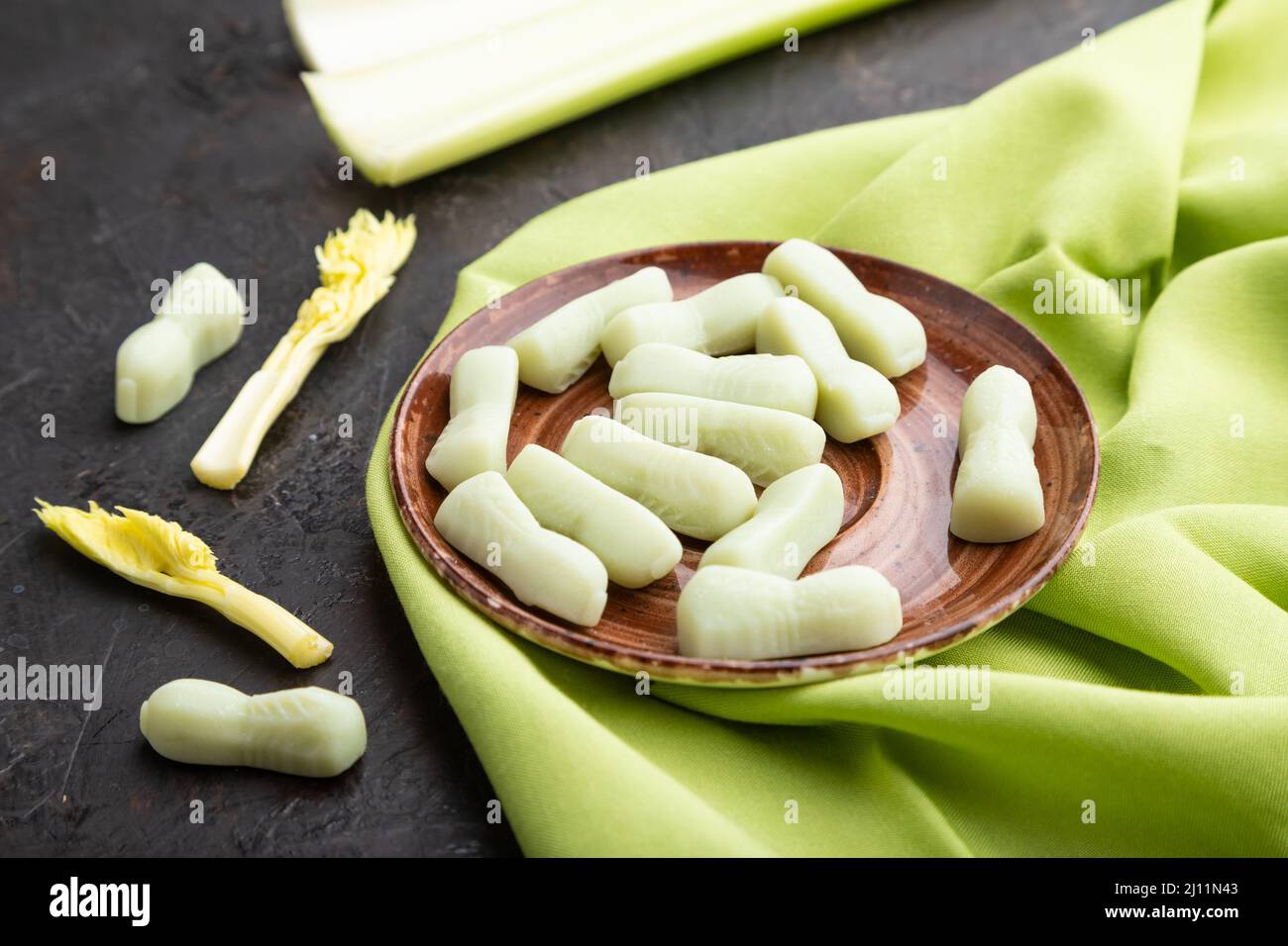 Jelly celery candies on black concrete background and green linen ...