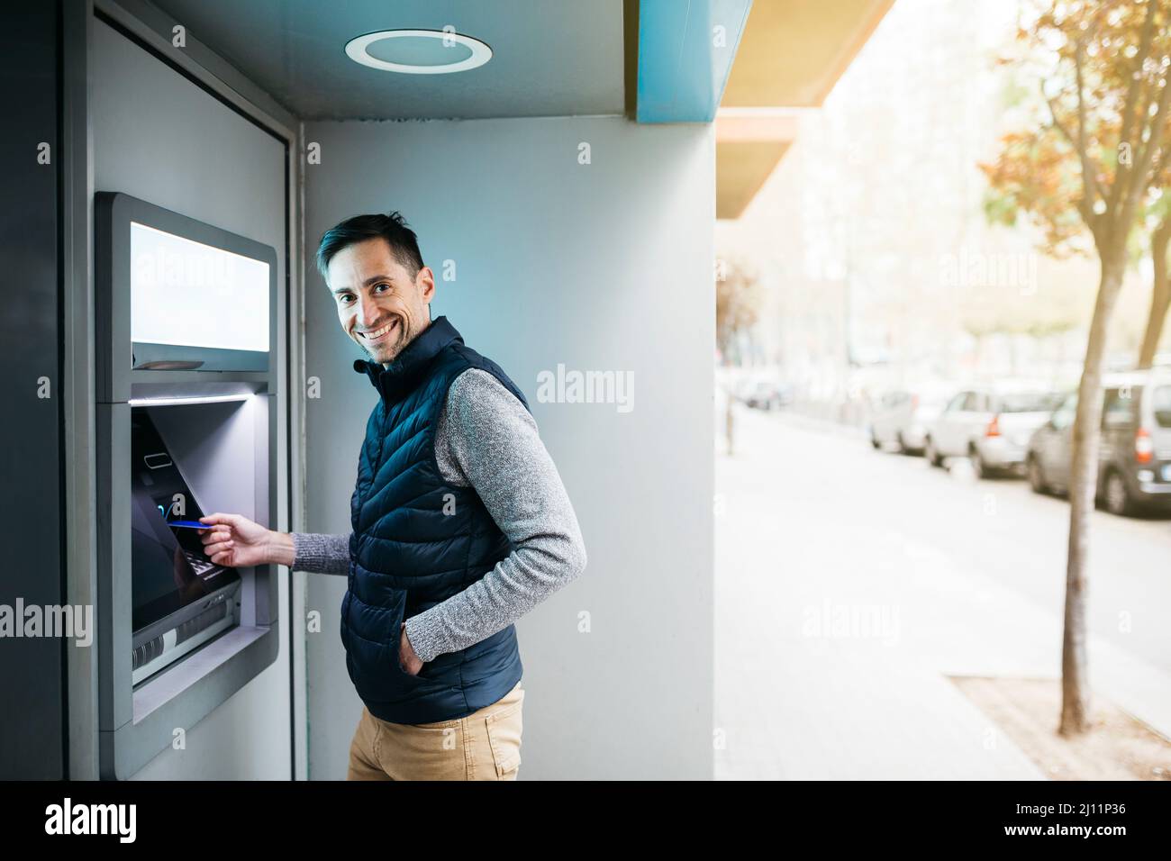 Man introducing a blue credit card to an ATM street machine Stock Photo ...