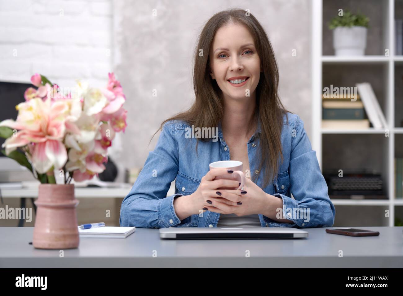 Young woman working online with laptop computer at home sitting at desk ...
