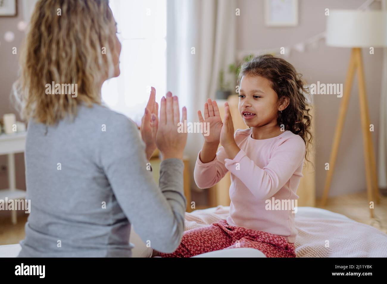 Happy mother with her little daughte playing clapping hands game on bed at home Stock Photo - Alamy