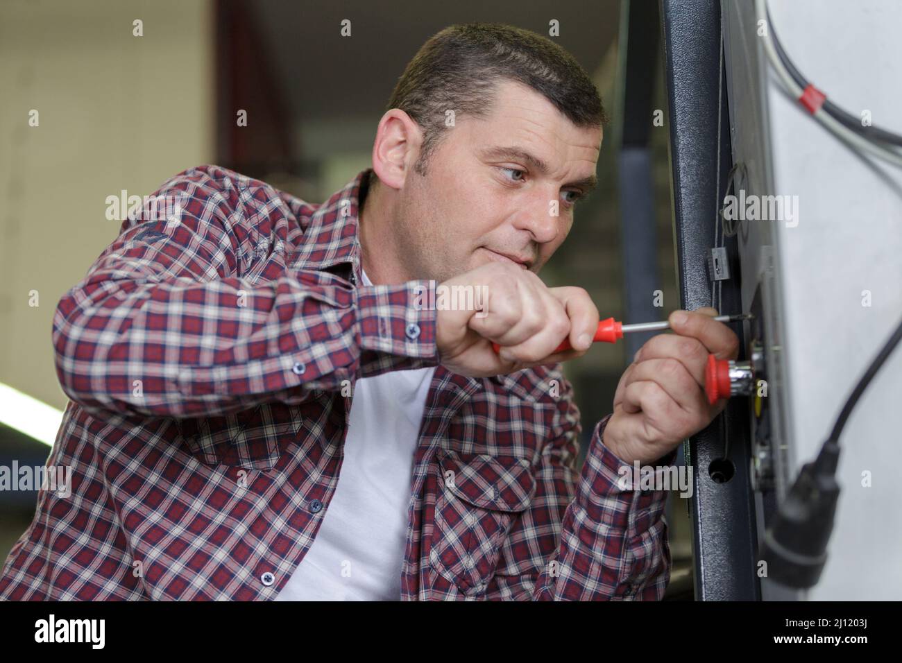engineer using screwdriver on industrial machinery Stock Photo - Alamy