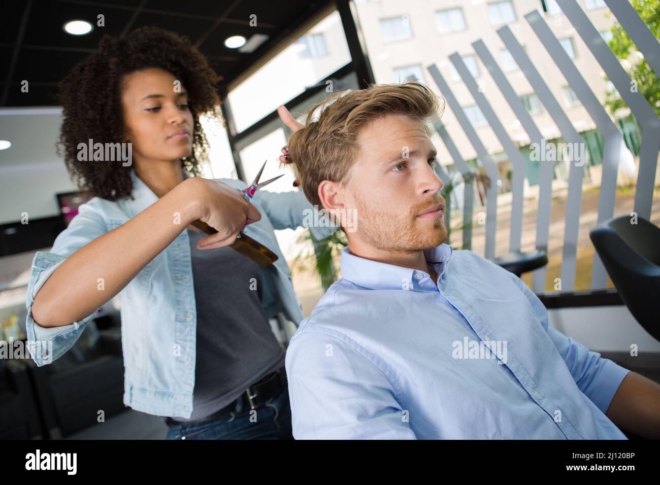 hairdresser cutting hair of male customer in salon Stock Photo - Alamy