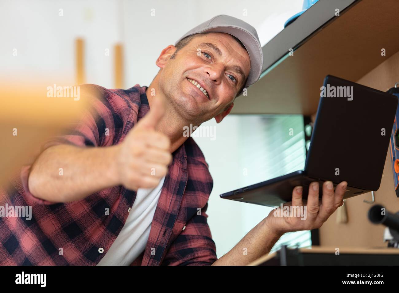 mature engineer holding laptop and showing thumbs-up Stock Photo - Alamy