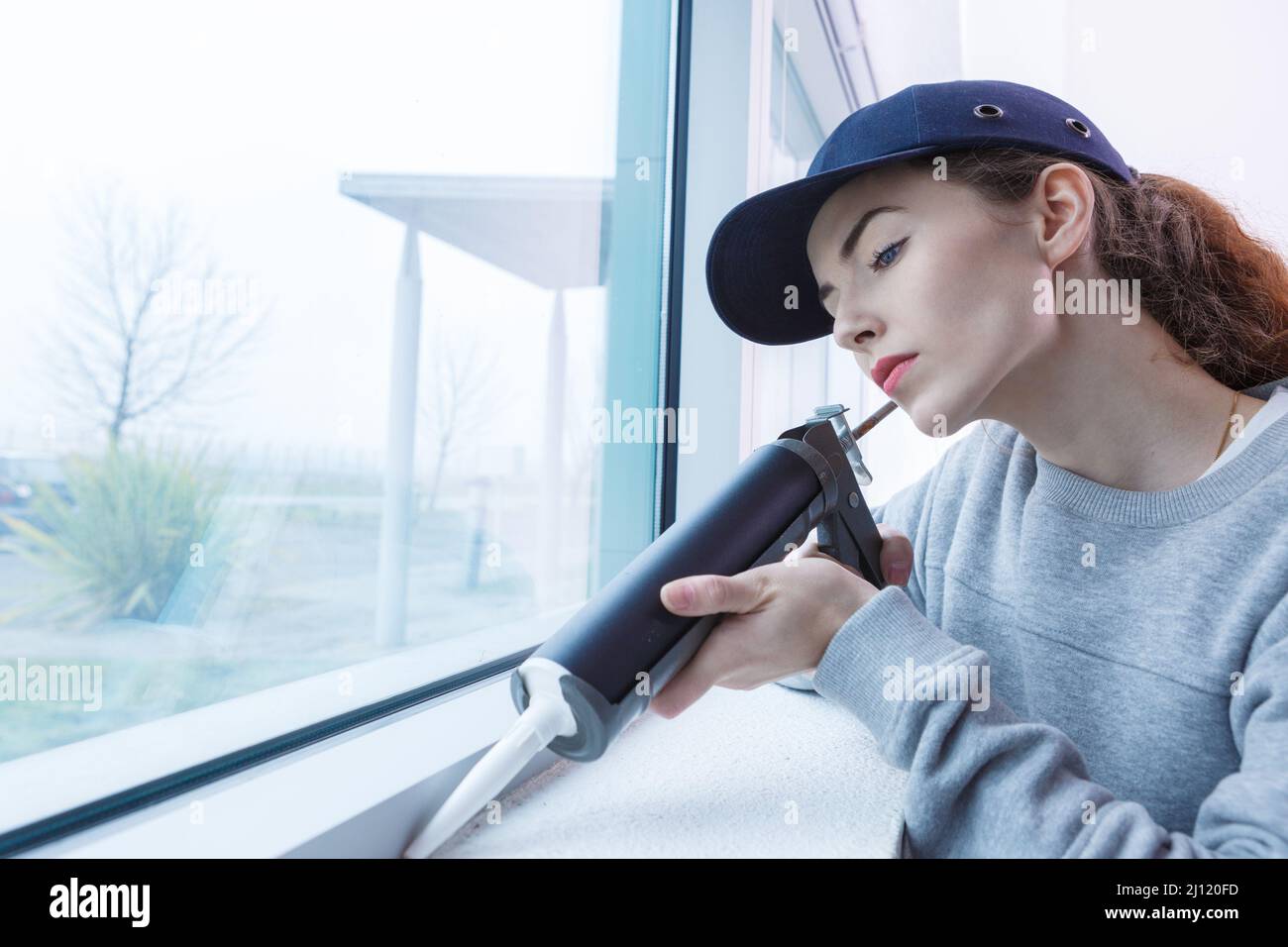 female window installer sealing the gaps with epoxy gun Stock Photo - Alamy