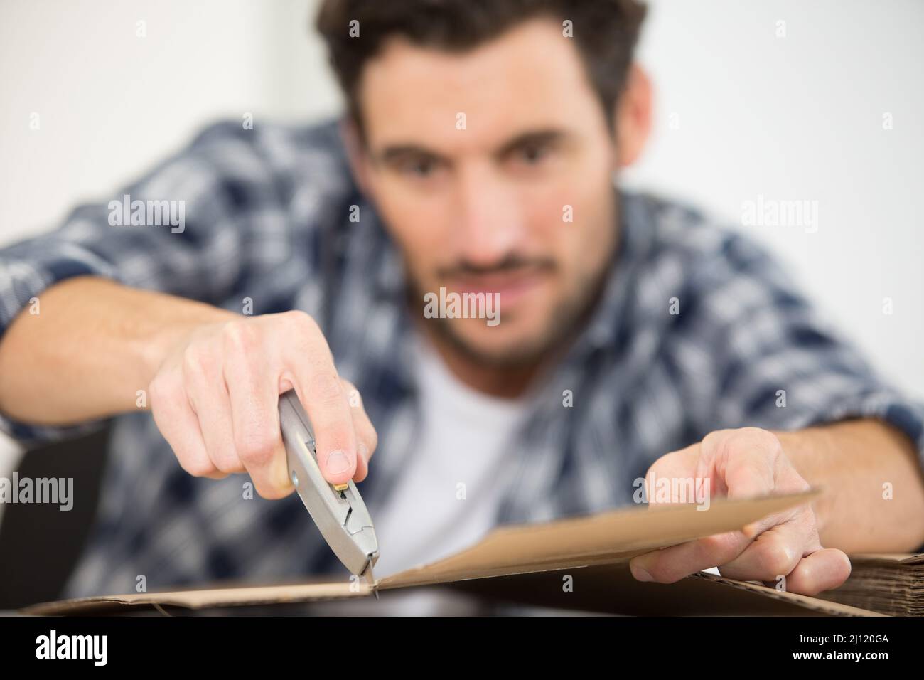 man cutting cardboard with a craft knife Stock Photo - Alamy