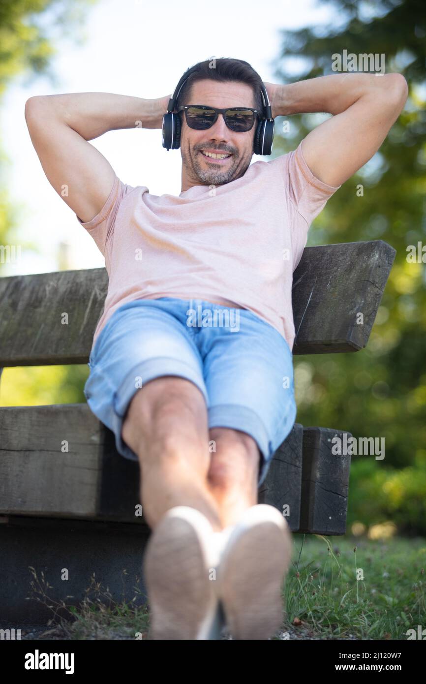 relaxed man listening music using headphones outdoors on bench Stock ...